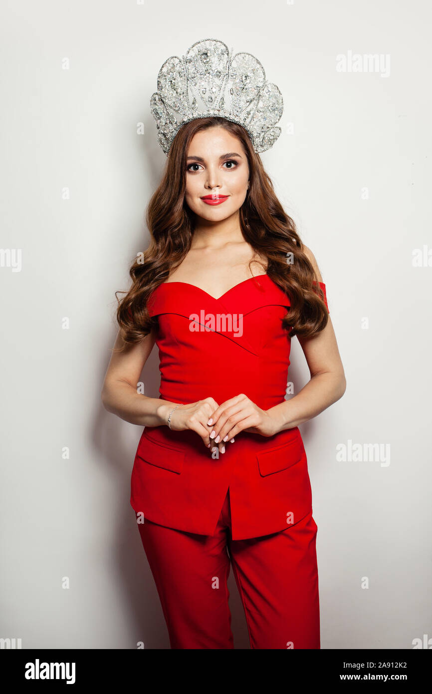 Beautiful model woman in red suit and diamond crown standing on white ...