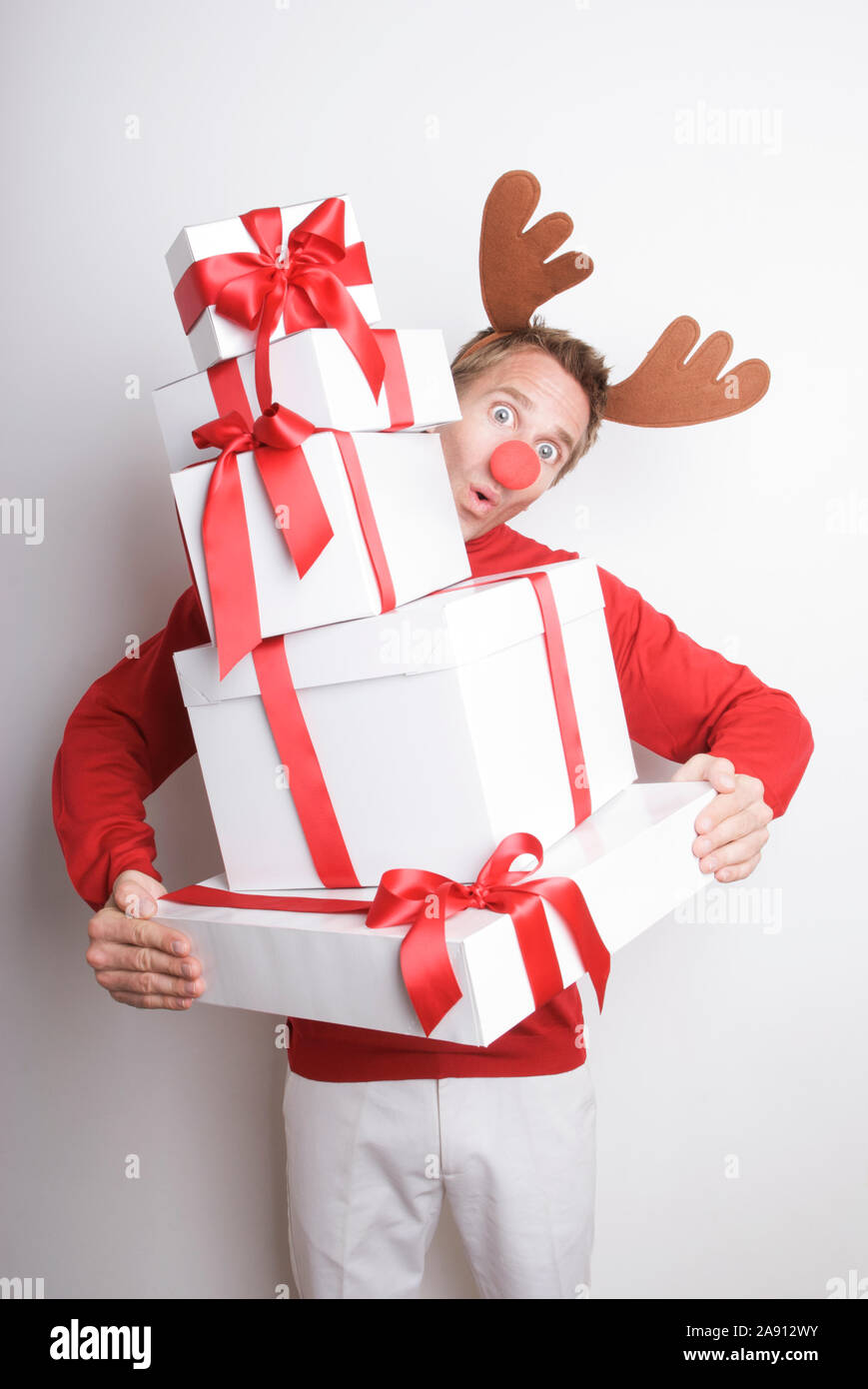 Red-nosed reindeer man standing holding a big stack of holiday presents ...