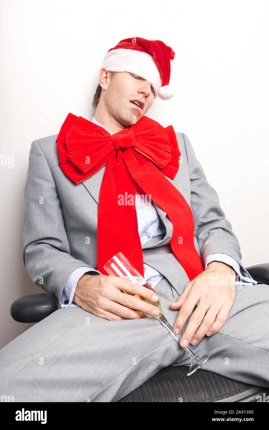 Office worker in Santa hat and big red bow sitting passed out drunk in ...