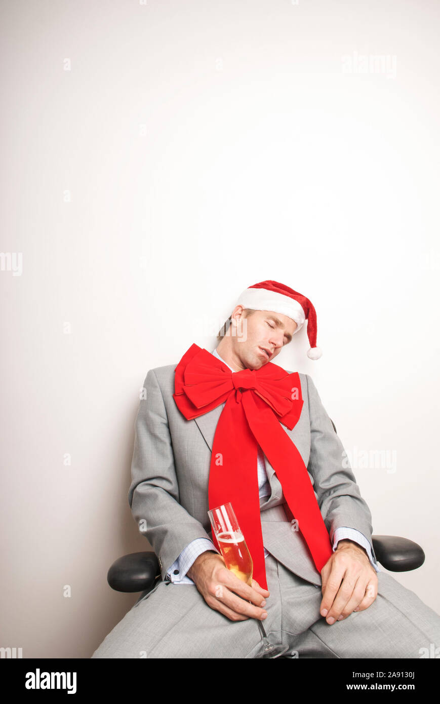Drunk office worker in Santa hat and big red bow sitting passed out in ...