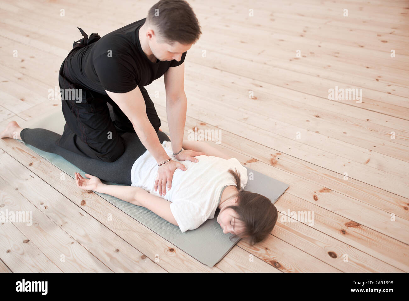 Man does back massage of woman lying on gray rug in gym Stock Photo - Alamy