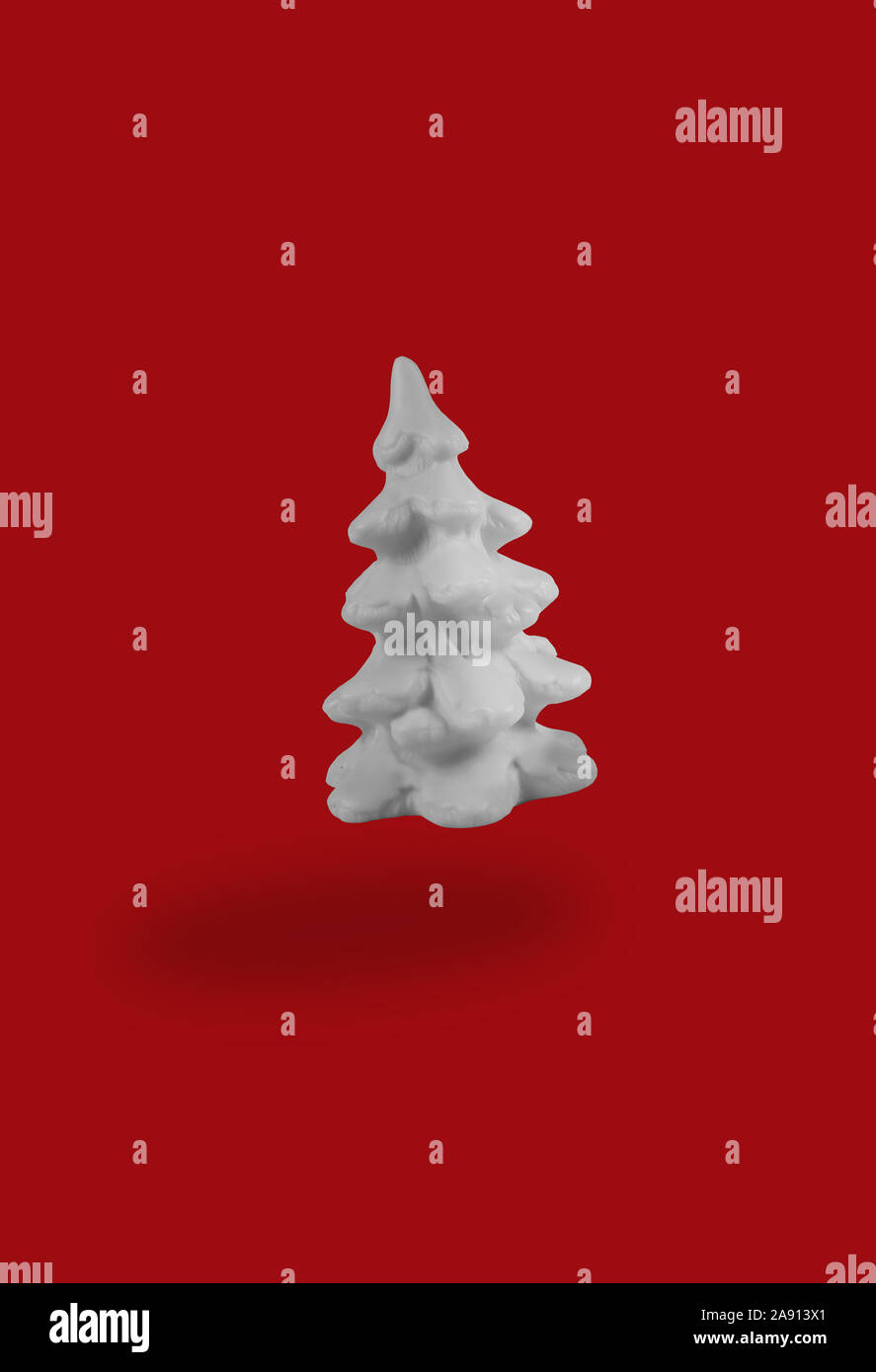 Floating christmas concept. White plastic fir falling on red background ...