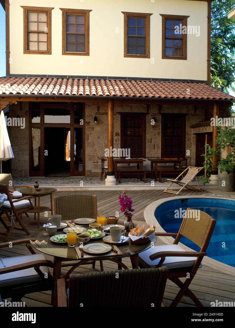 Table laid for lunch on decking beside swimming pool in front of small ...