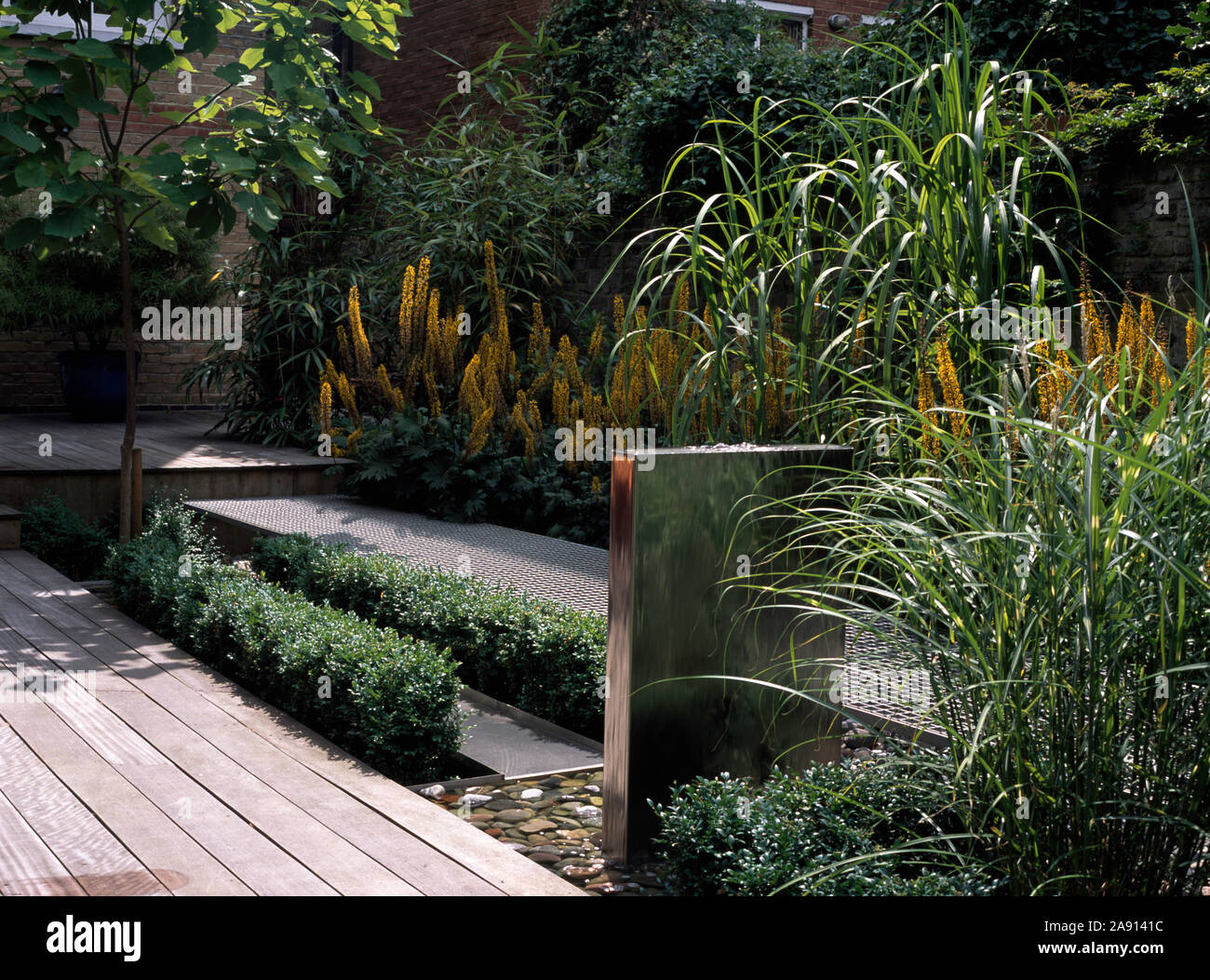 Small formal town garden with water rill and massed planting of grasses ...