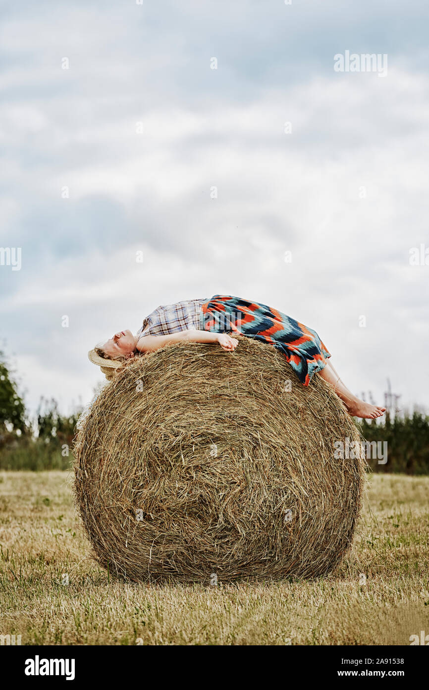 Girl lying on bale of hay Stock Photo - Alamy
