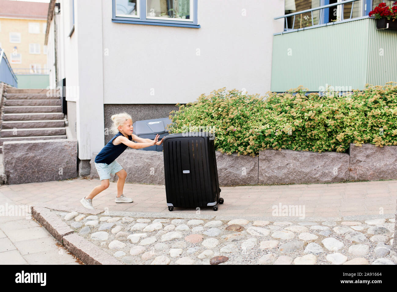 Girl pushing suitcase Stock Photo - Alamy
