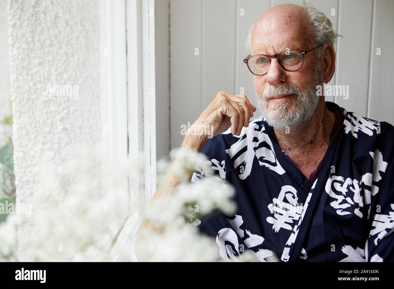 Senior man looking through window Stock Photo - Alamy