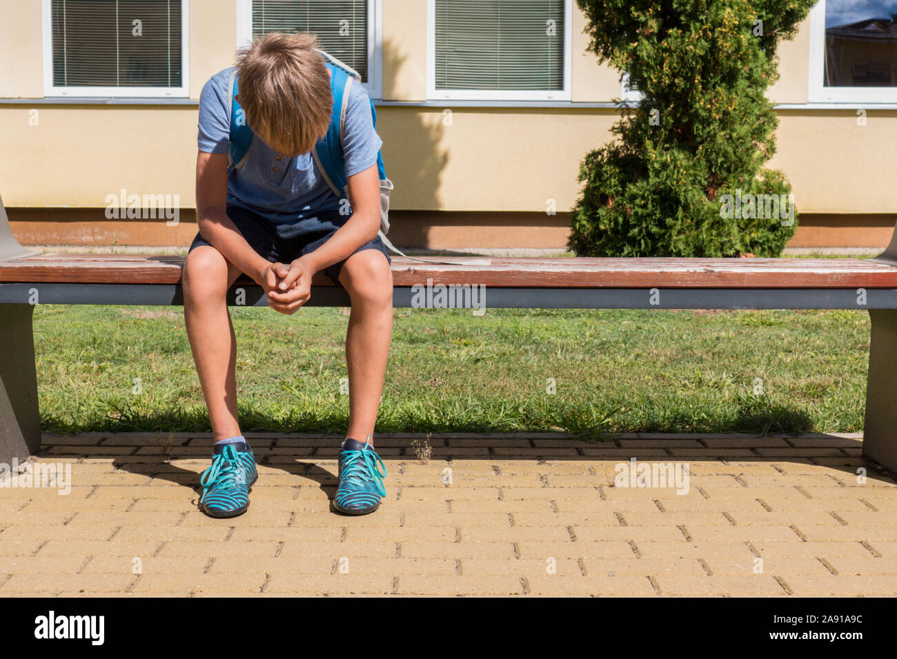 Unhappy sad boy sitting in closed position with his head down. School ...