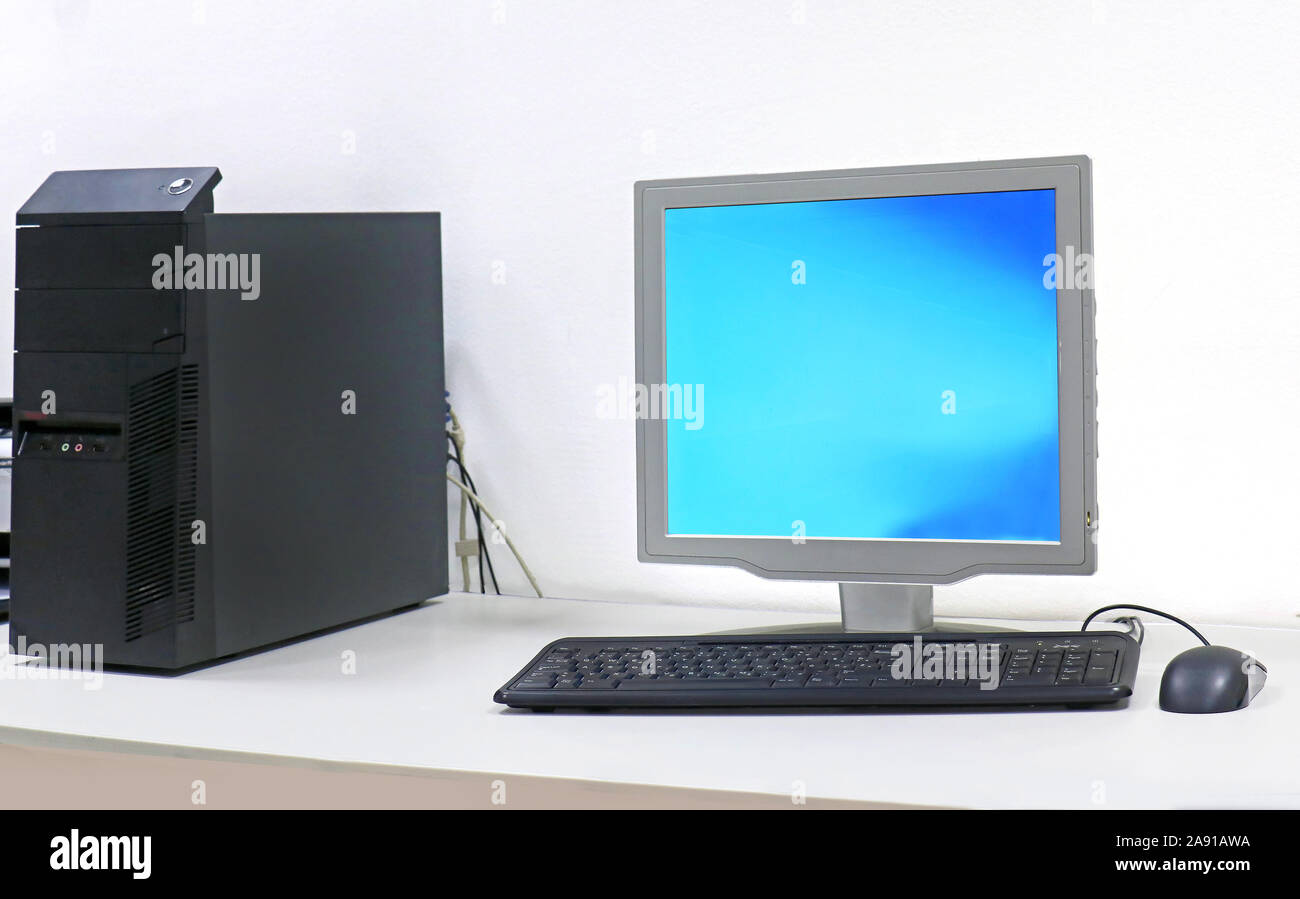 Computer with blue screen and keyboard inside modern room interior ...