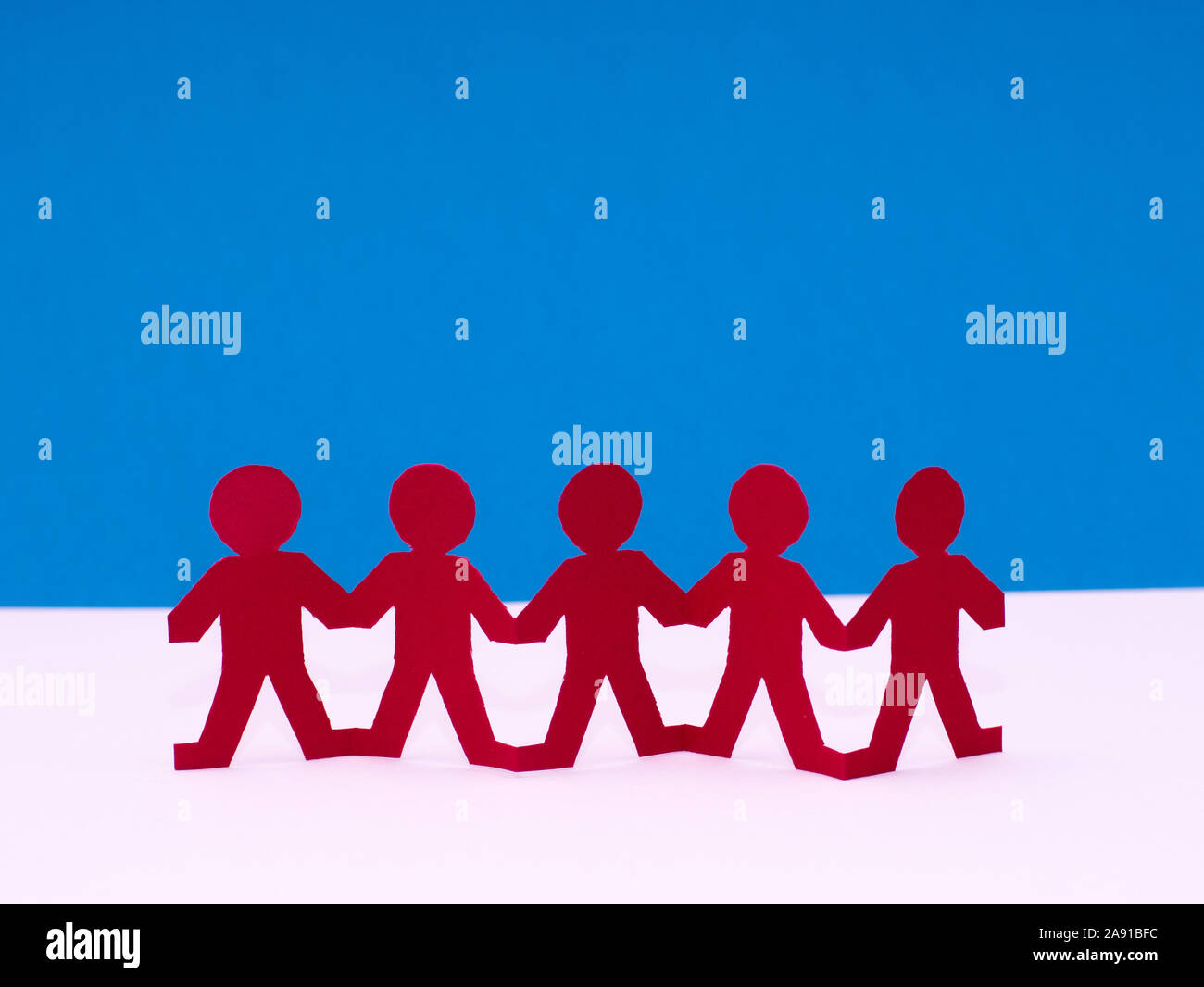 Team of paper chain people in a row on paper background holding hands ...