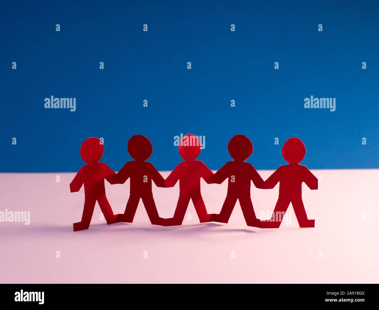 Team of paper chain people in a row on paper background holding hands ...