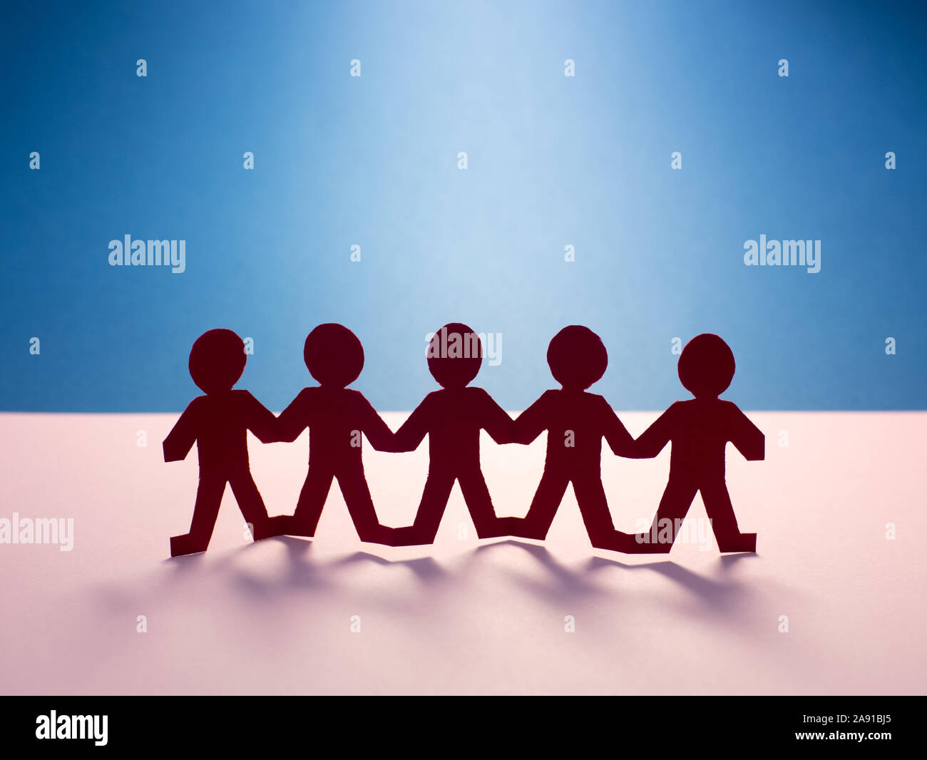 Team of paper chain people in a row on paper background holding hands ...