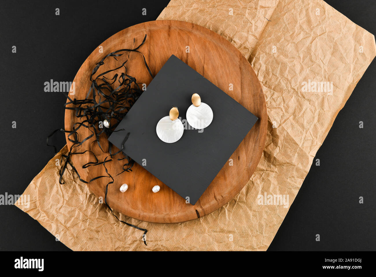 Round white earrings. Close-up. Golden latch. Laid out on a wooden ...