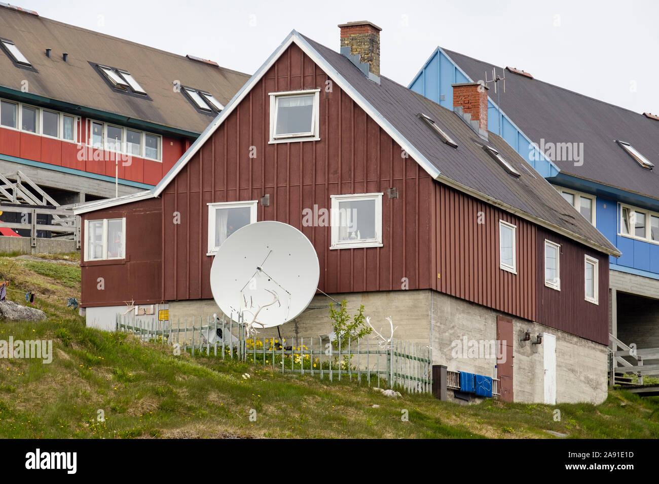 Large satellite dish outside a typical Inuit house built from wood and ...