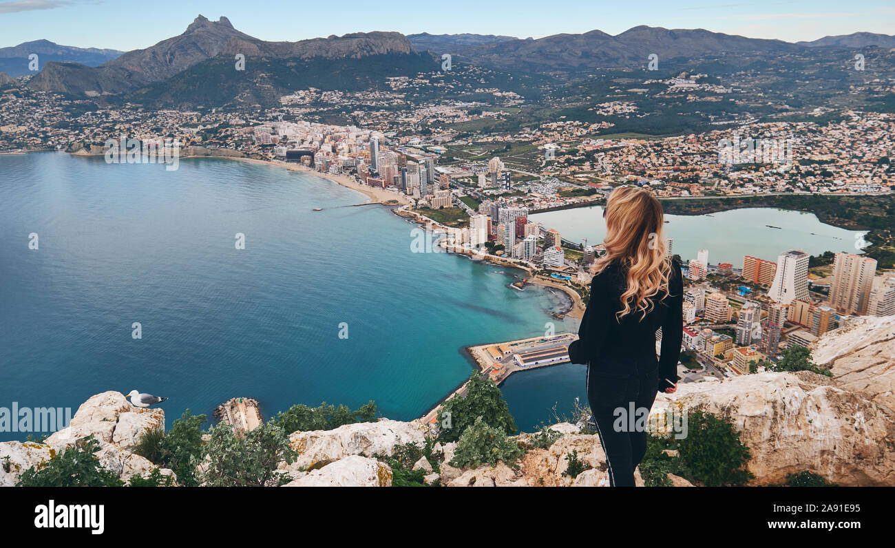Rear view woman climbed up on peak of Penon de Ifach rock enjoy ...