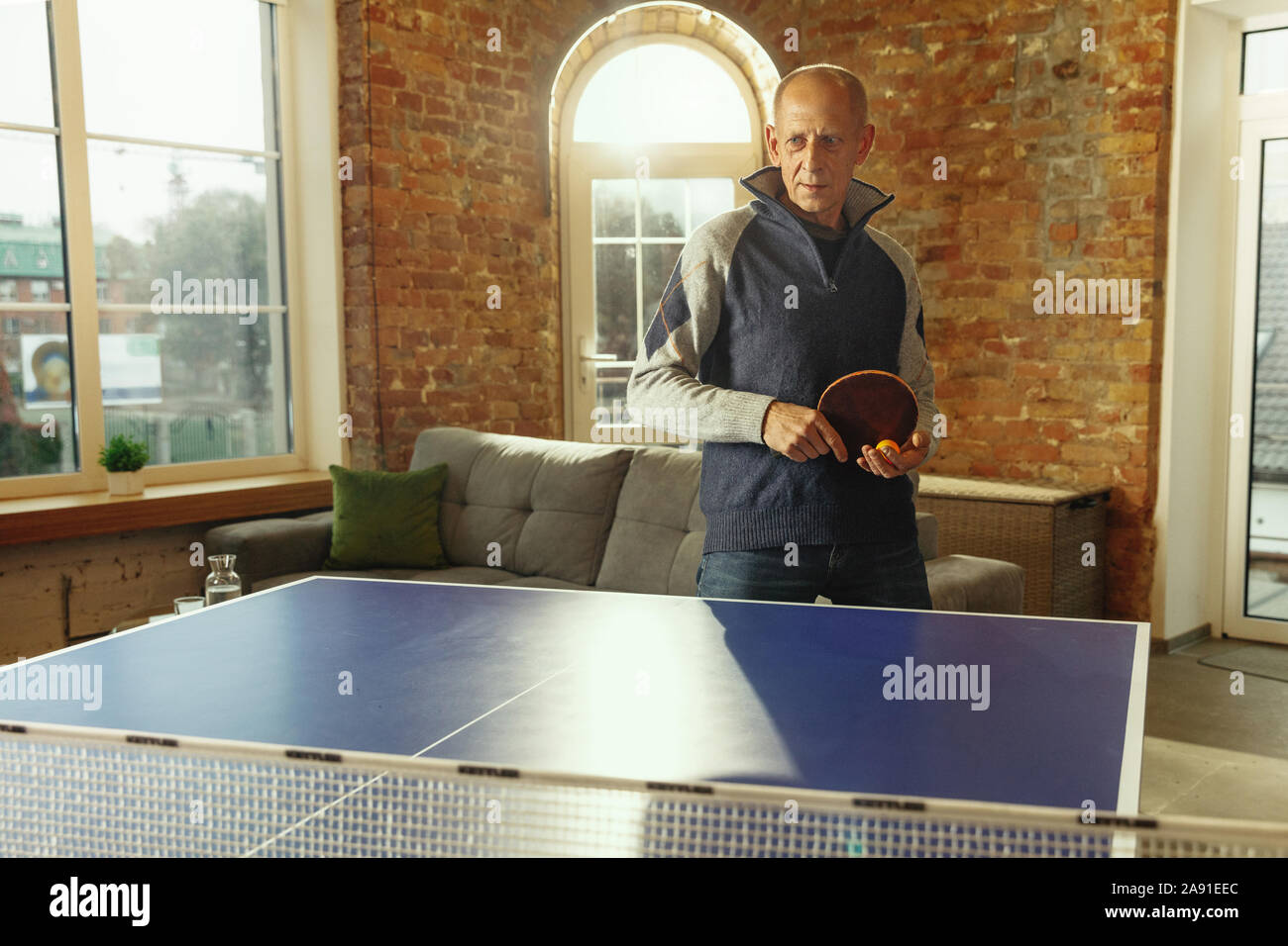 Senior man playing table tennis in workplace, having fun. Male model in ...