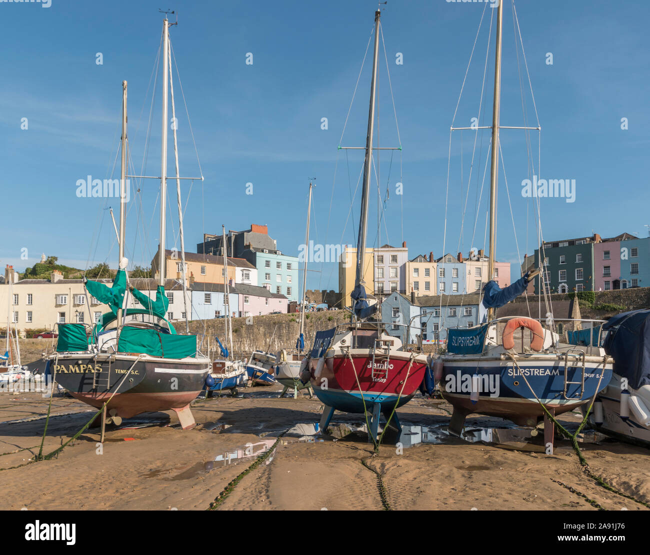 Boats stranded by the low tide in the pretty harbour of Tenby on a ...