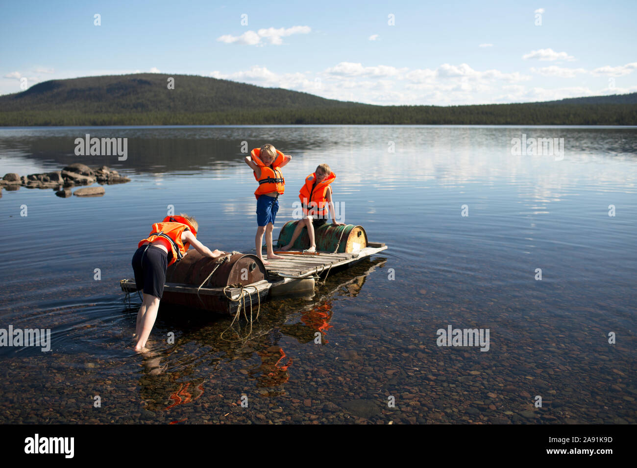 Boys on wooden raft Stock Photo - Alamy