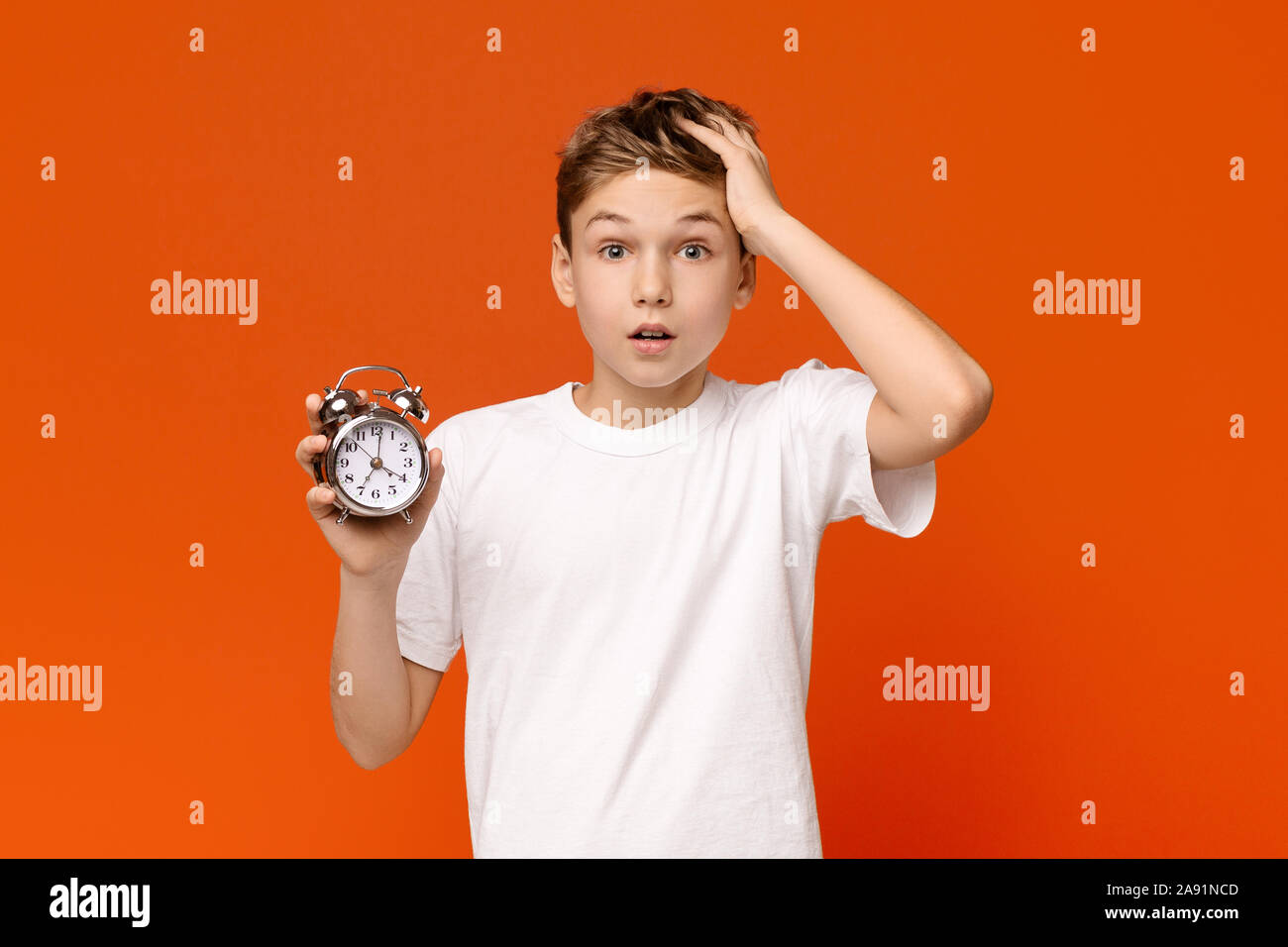 Worried awake teen boy with alarm clock Stock Photo - Alamy