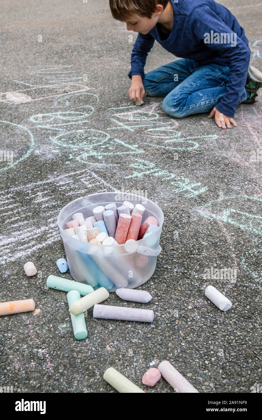 Young boy drawing outside on the sidewalk with chalk Stock Photo - Alamy