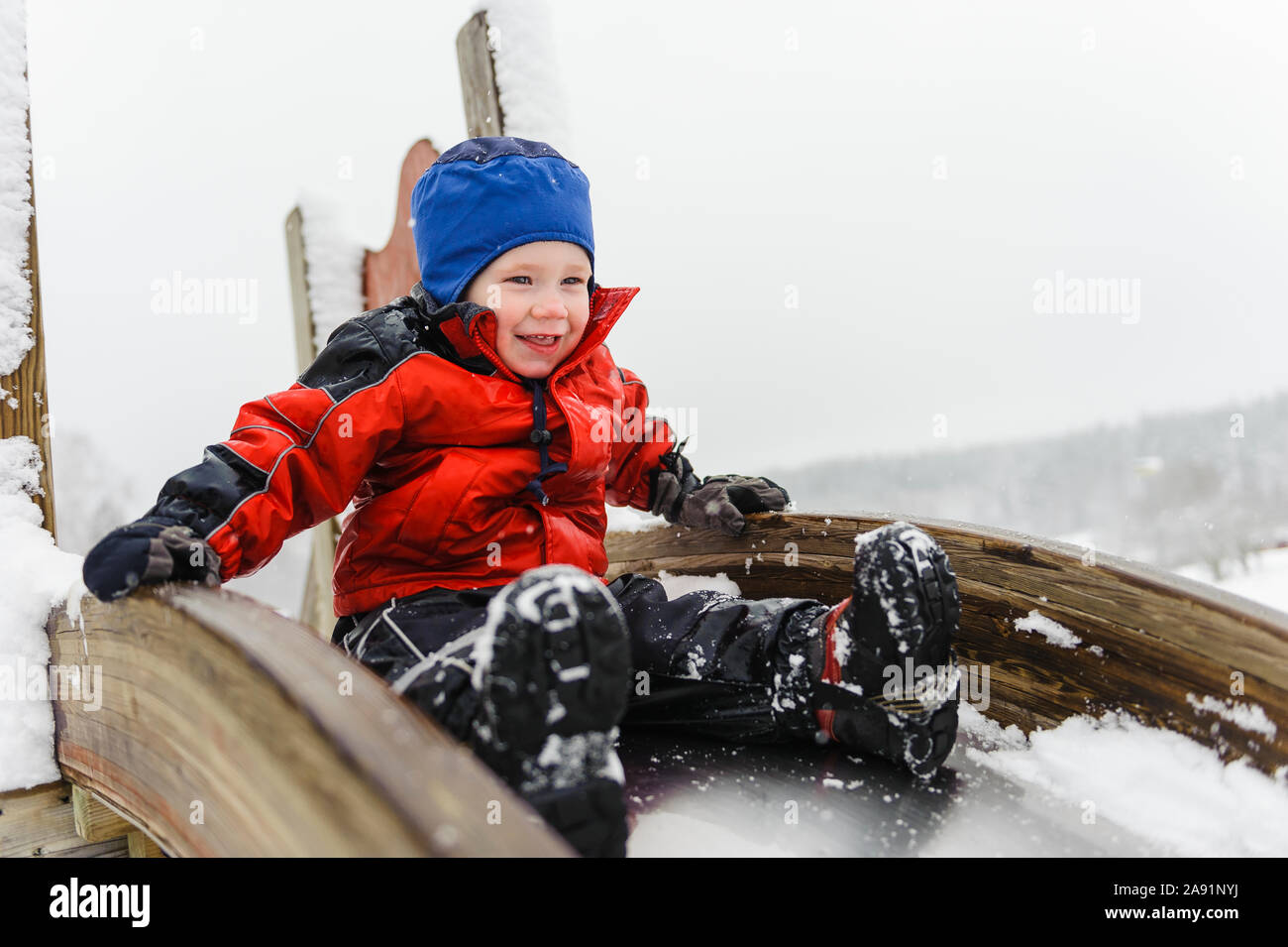 Boy on slide at winter Stock Photo - Alamy