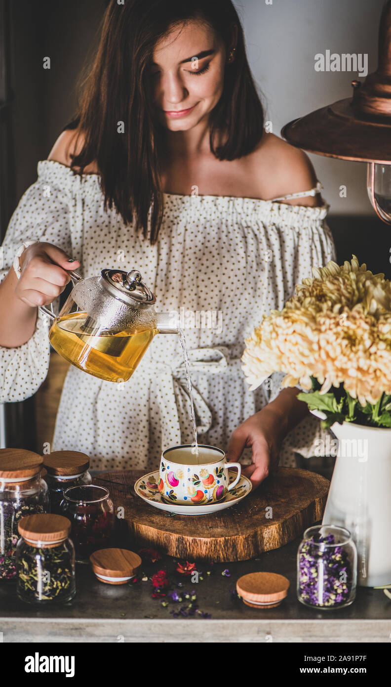 Young smiling woman pouring tea from pot into porcelain cup Stock Photo ...