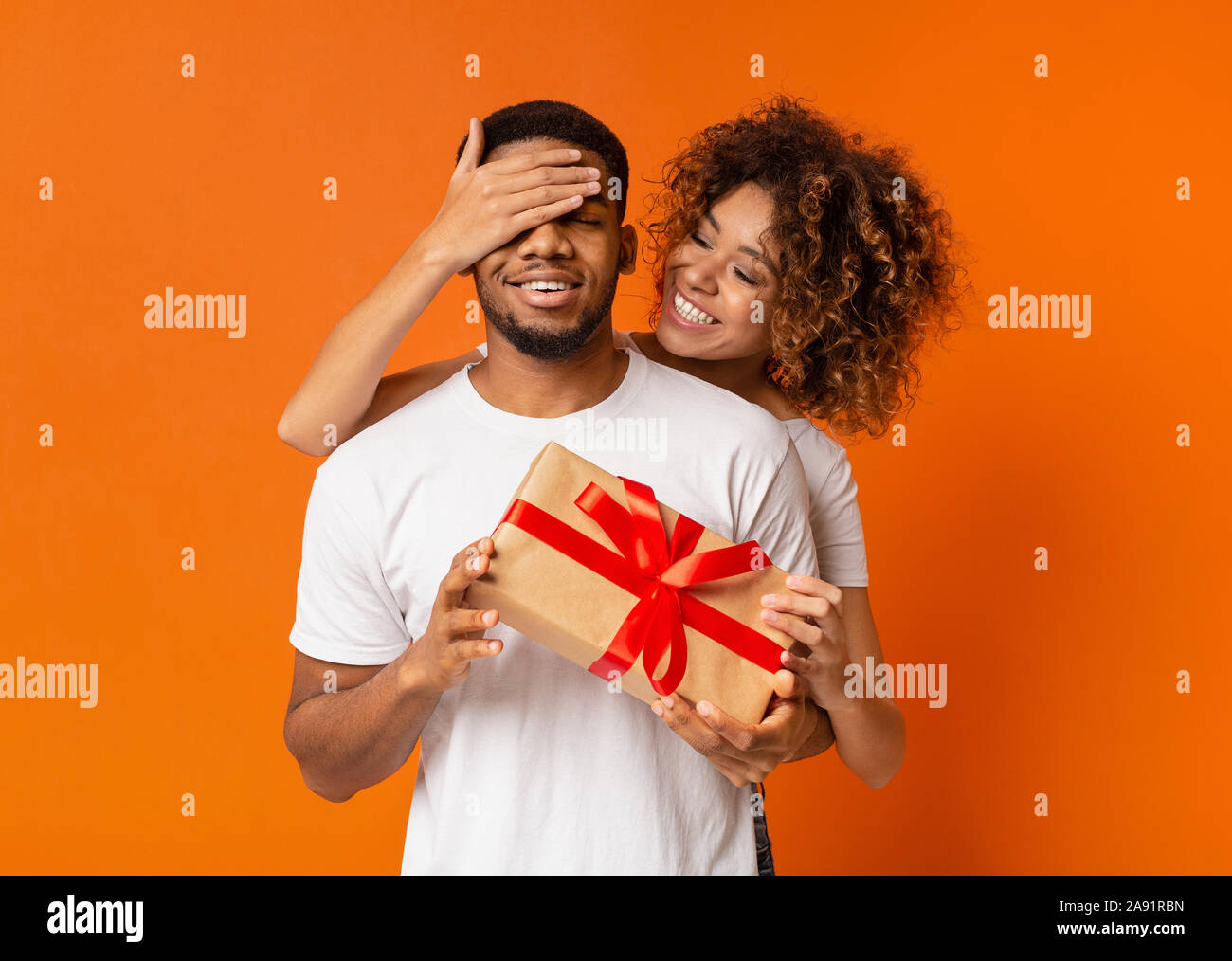 Beautiful girl covering her boyfriend eyes with present Stock Photo - Alamy