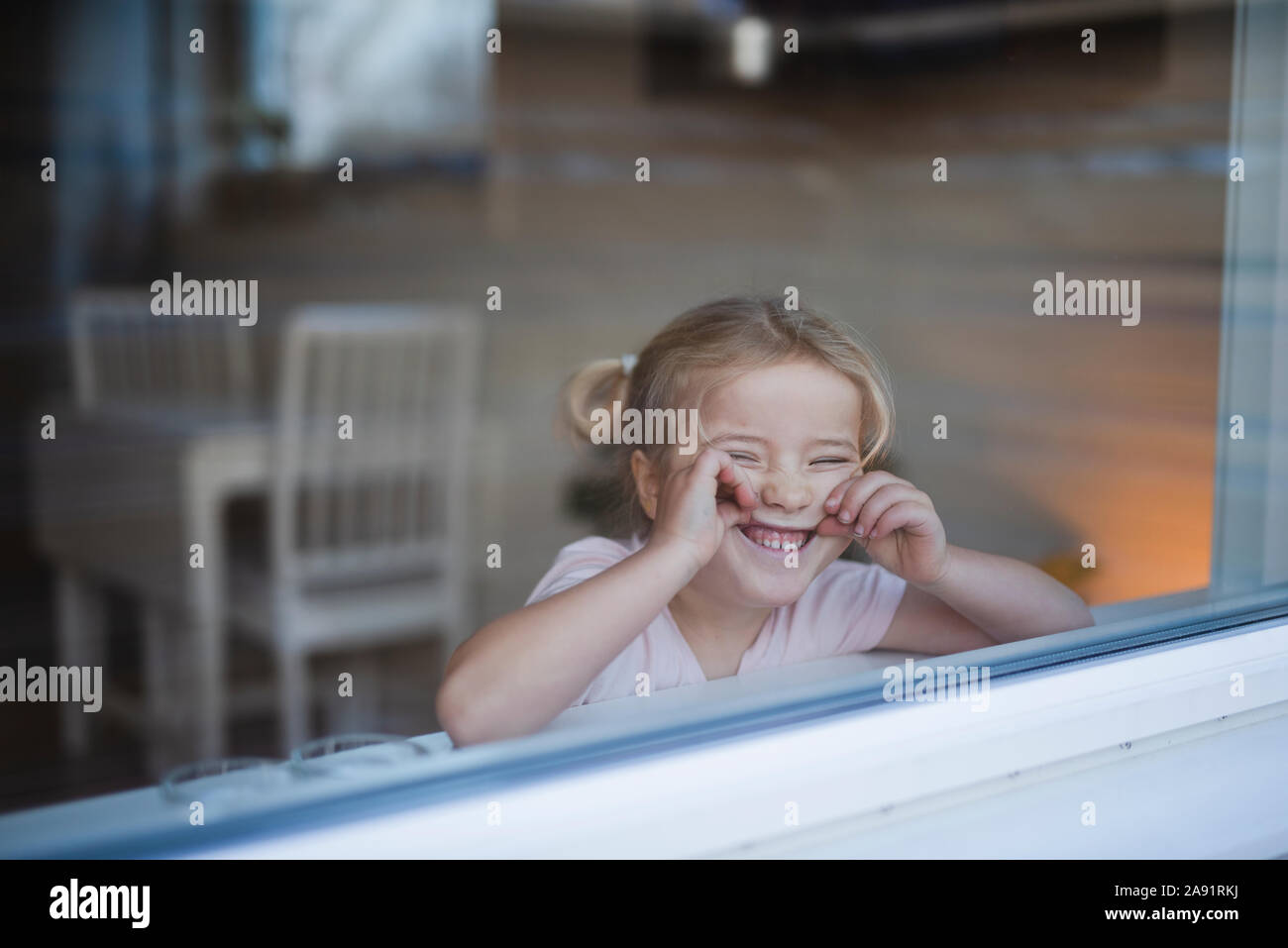Girl looking through window Stock Photo - Alamy