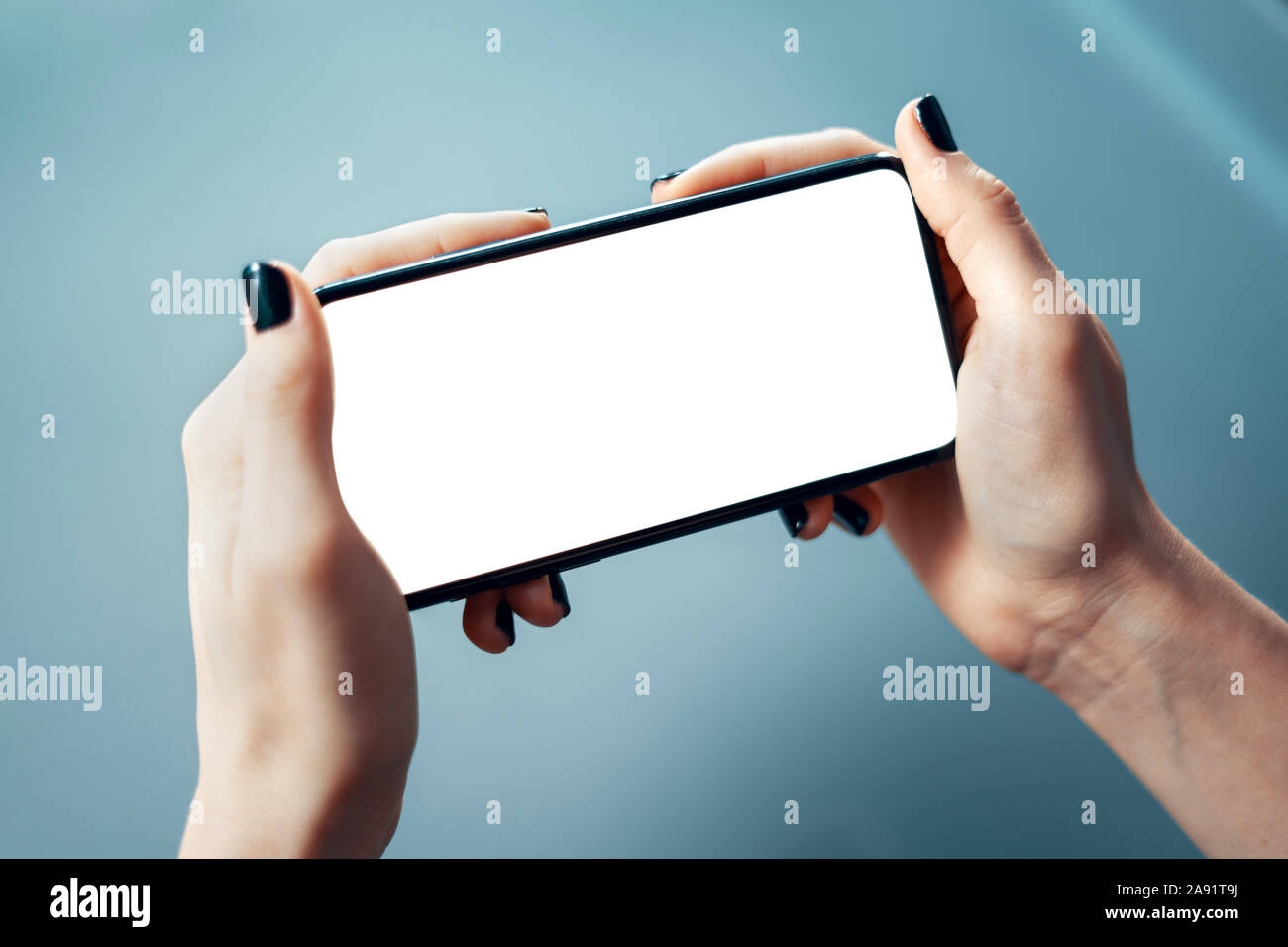 Close-up image of female holding smartphone horizontally with both ...