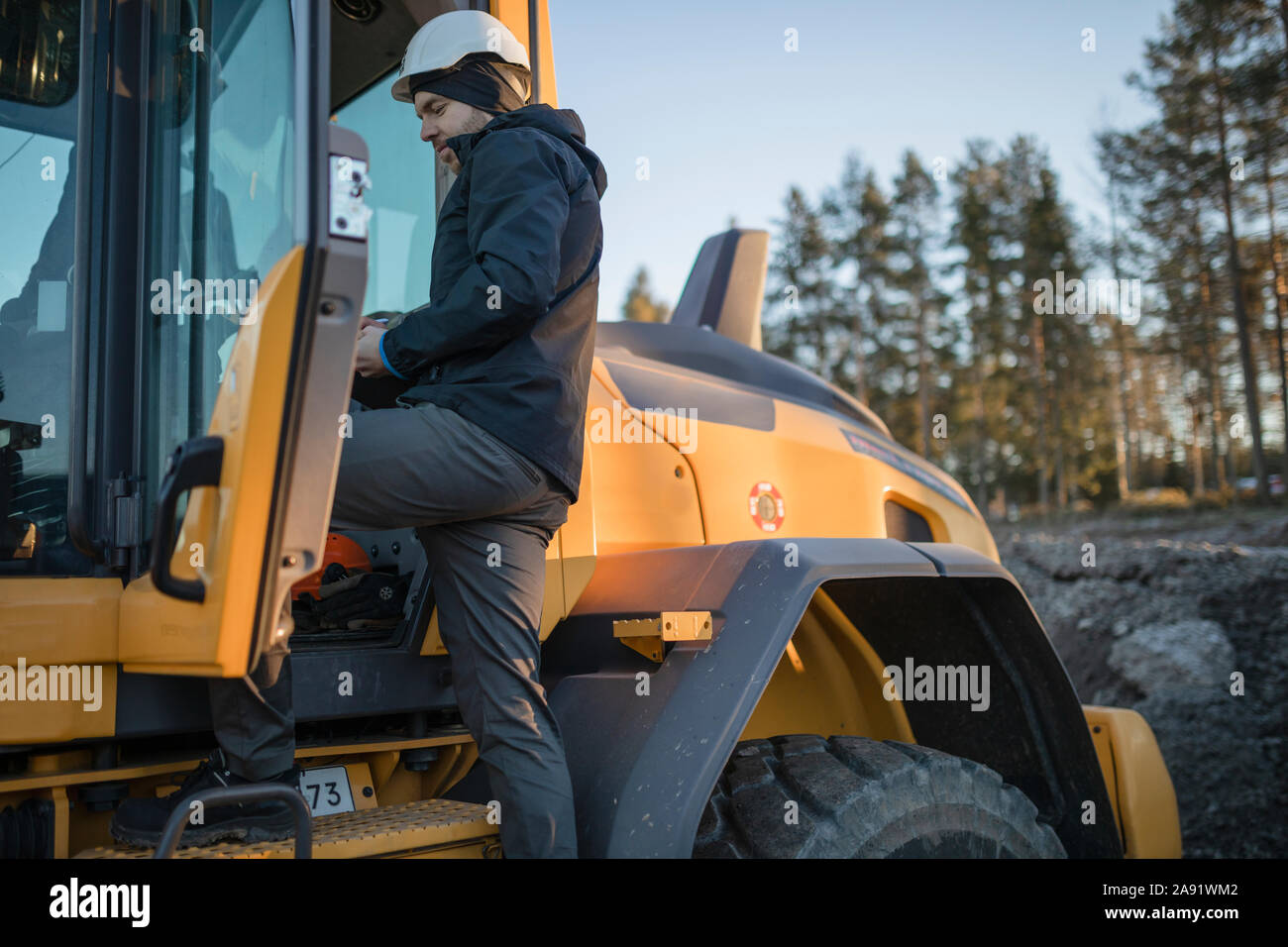 Man entering digger Stock Photo - Alamy