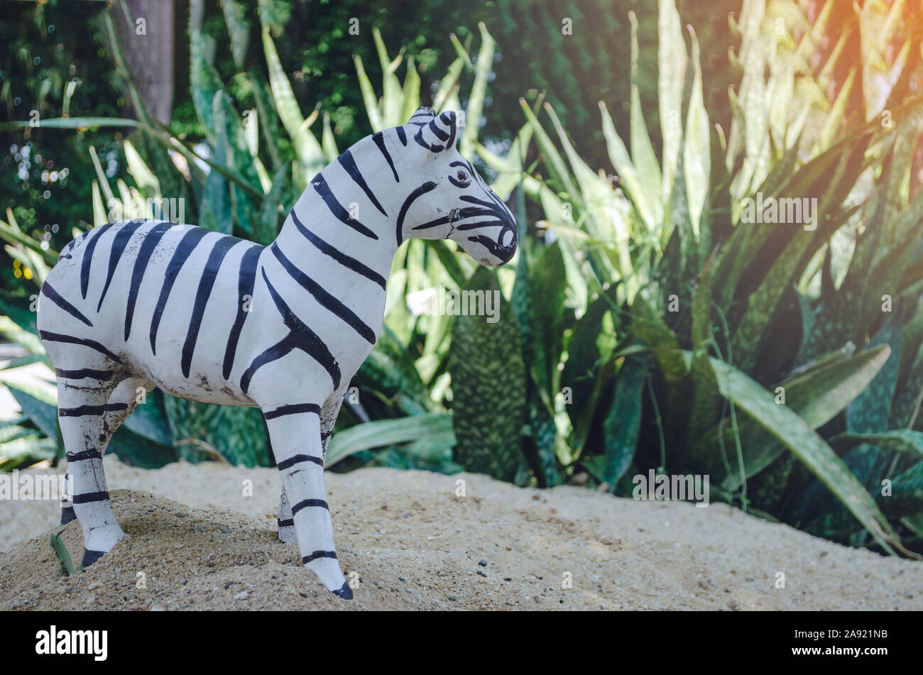 The zebra statue stands on a pile of sand. With a garden backdrop Stock ...