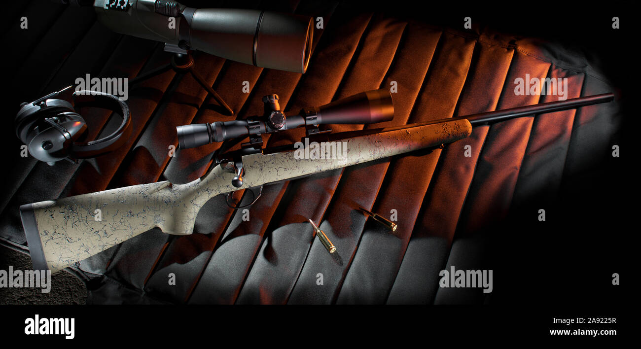 Bolt action rifle on a shooting mat with hearing protection and ...