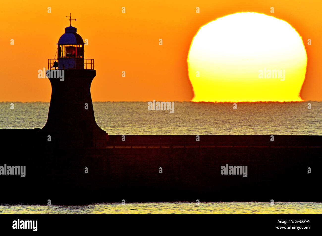 Large sun at sunrise and lighthouse Stock Photo - Alamy