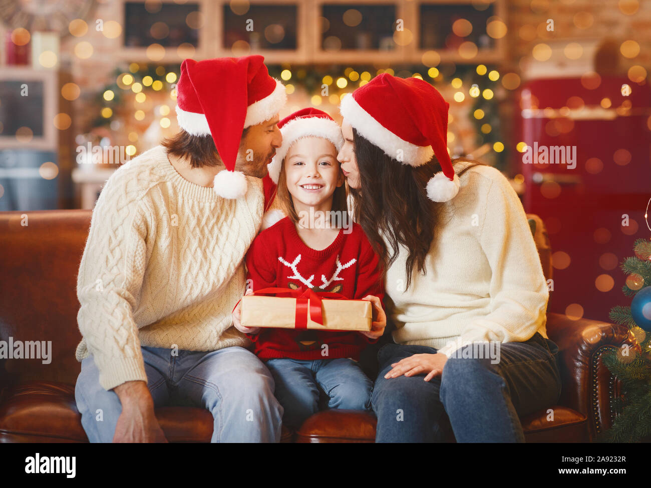 Parents in santa hats kissing daughter on Christmas eve Stock Photo - Alamy