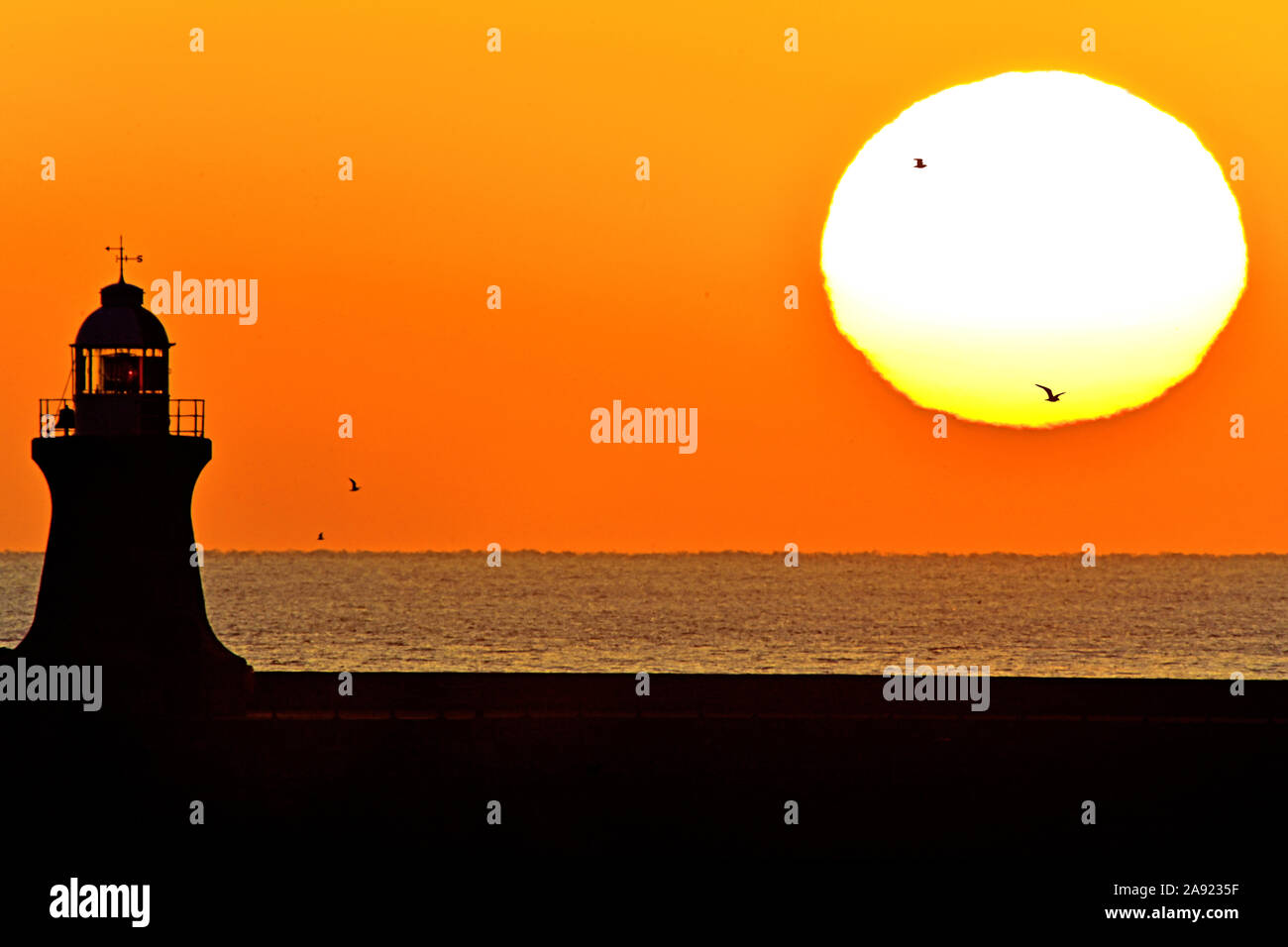 Large sun at sunrise and lighthouse Stock Photo - Alamy
