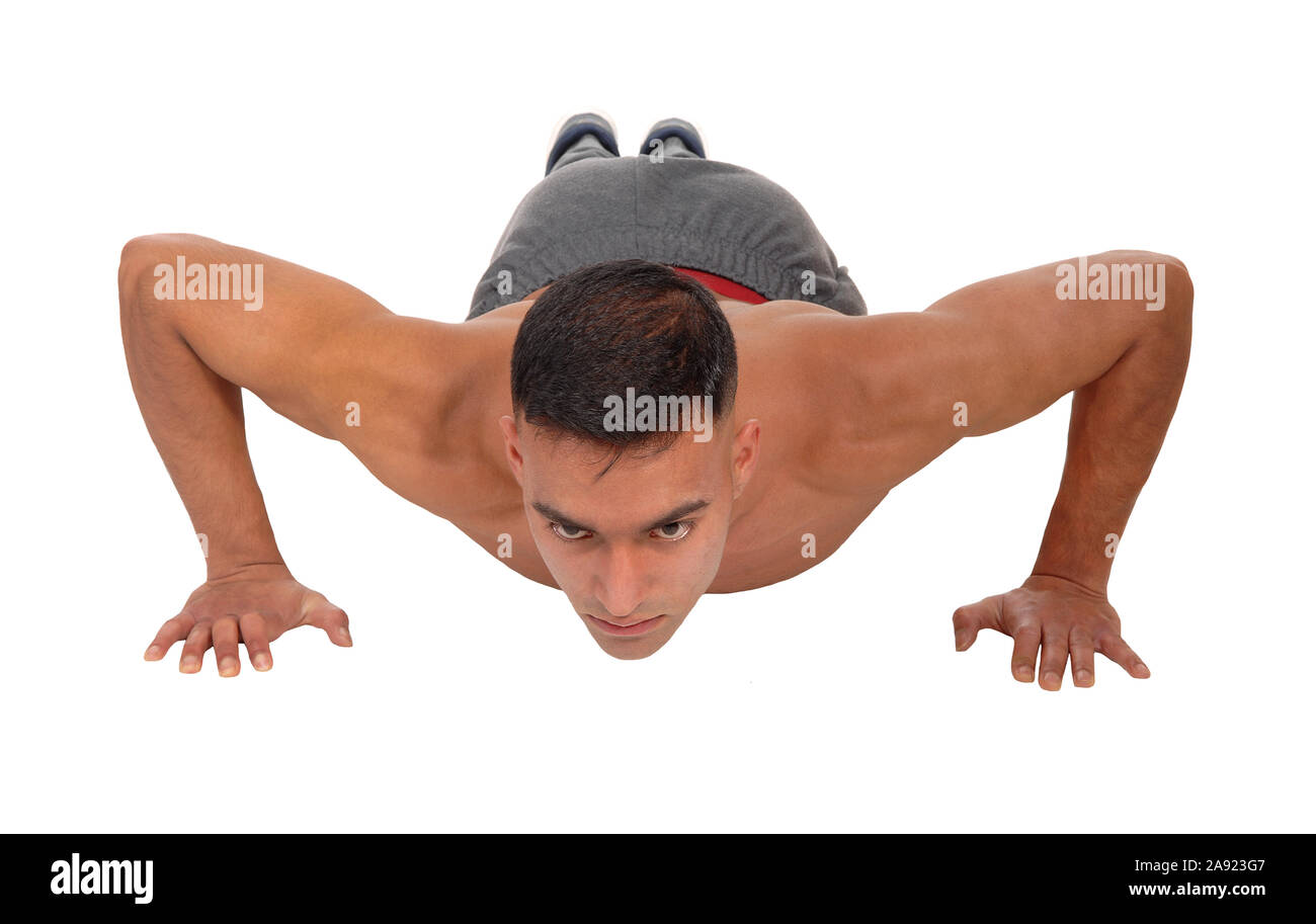 A young east Indian man doing his push aps on the floor in the studio ...