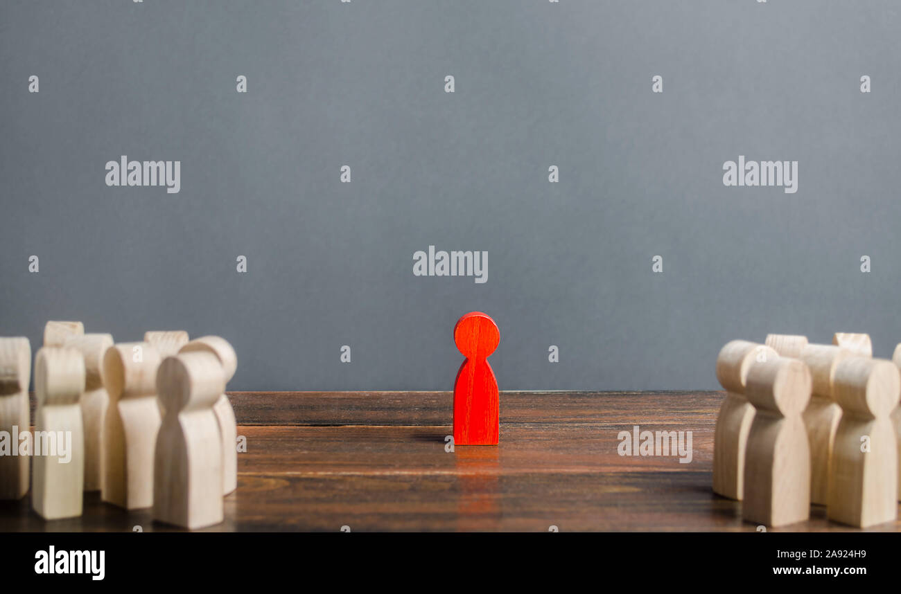 red figurine of a man stands aside from the crowd of people. Asociality ...