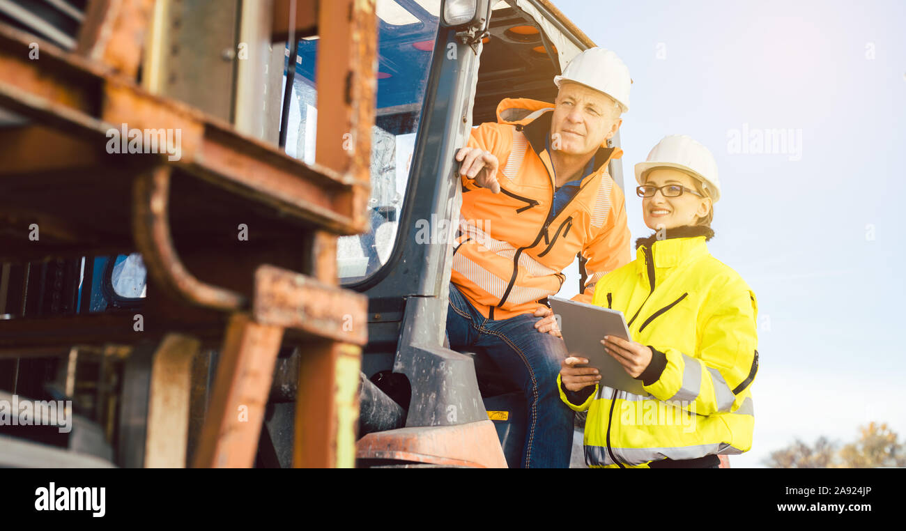Worker in forklift and forewomen looking into task list Stock Photo - Alamy