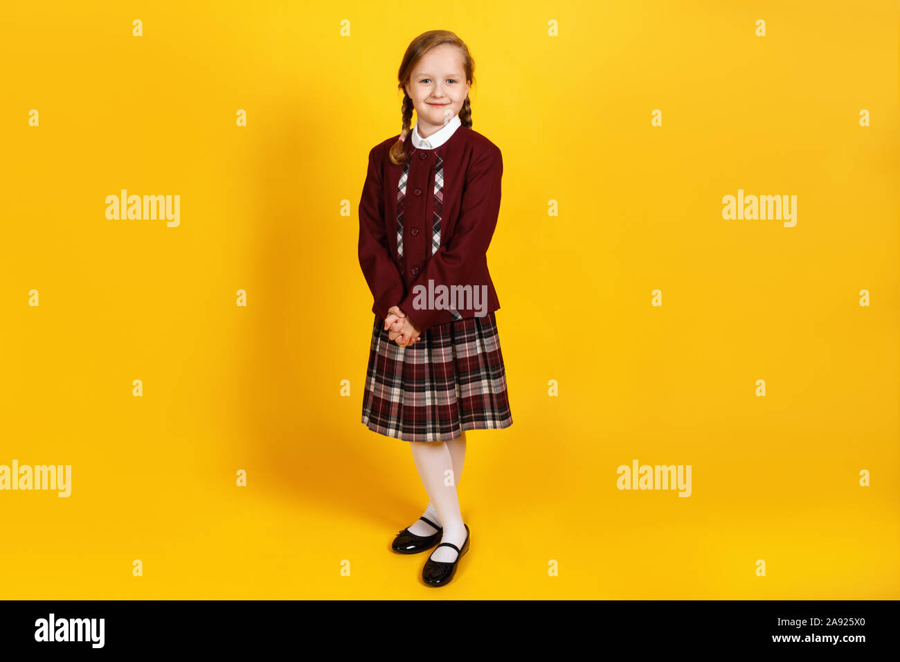 A full-length schoolgirl stands and looks at the camera. Cute little ...