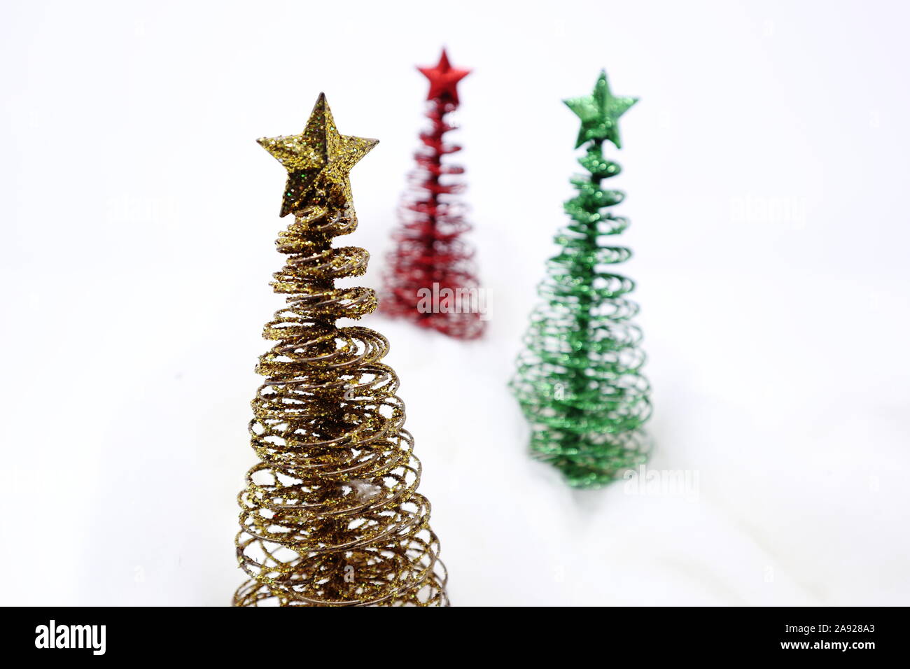 three toy Christmas trees (green, red, and gold) with start on top, on ...