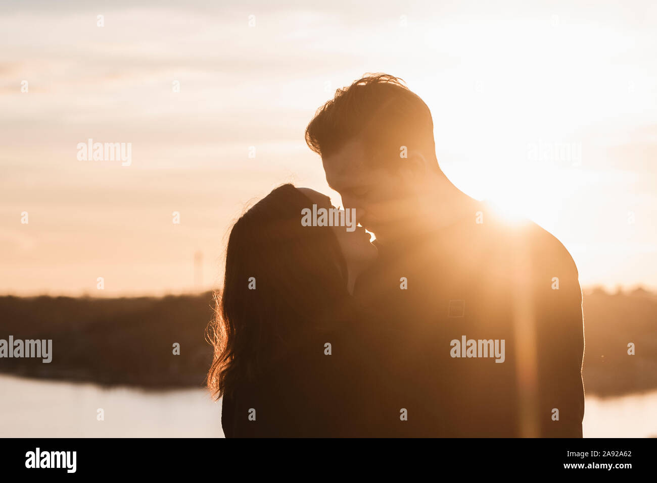 Couple kissing at sunset Stock Photo - Alamy