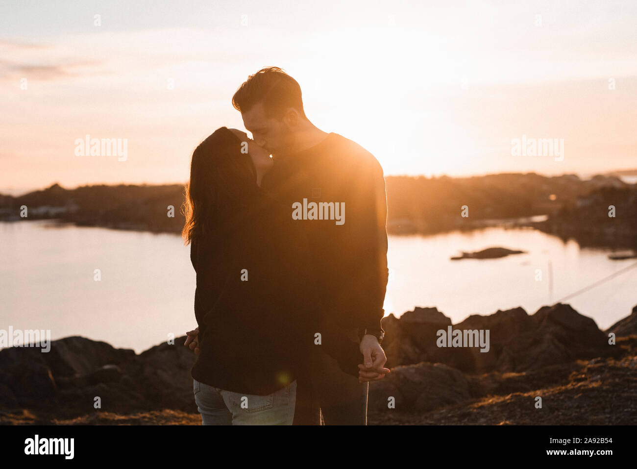 Couple kissing at sunset Stock Photo - Alamy