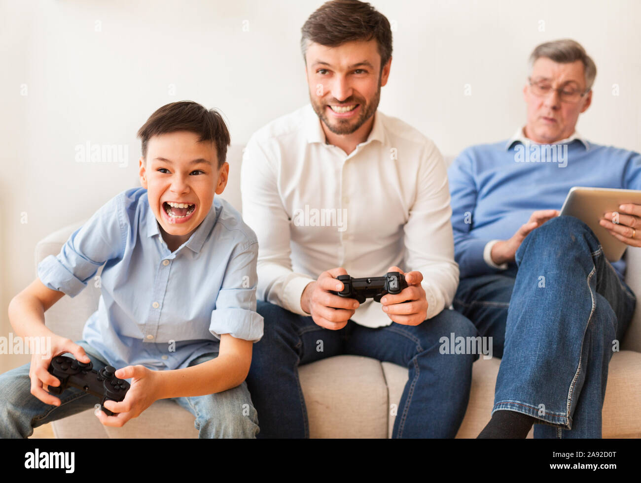 Boy Playing Video Games With Dad And Grandpa At Home Stock Photo - Alamy
