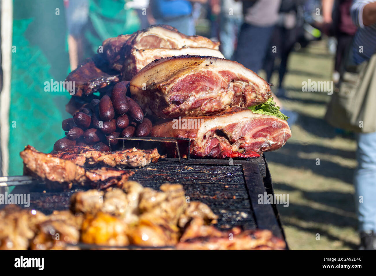 A pile of grilled and smoked meat and sausages. Chunks of pork are ...