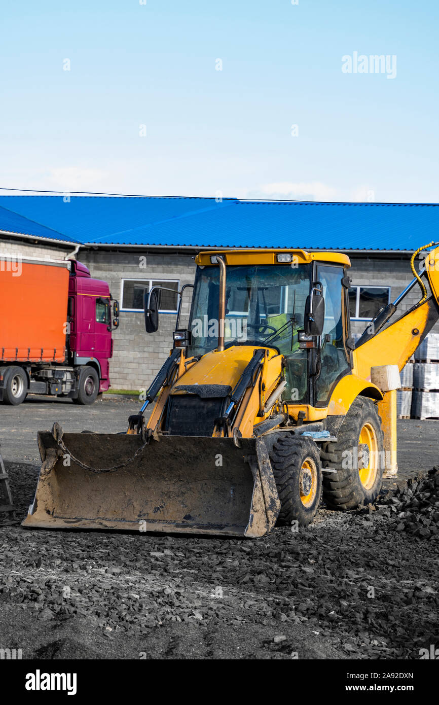 The yellow all-wheel drive backhoe loader stands on the yard ready for ...