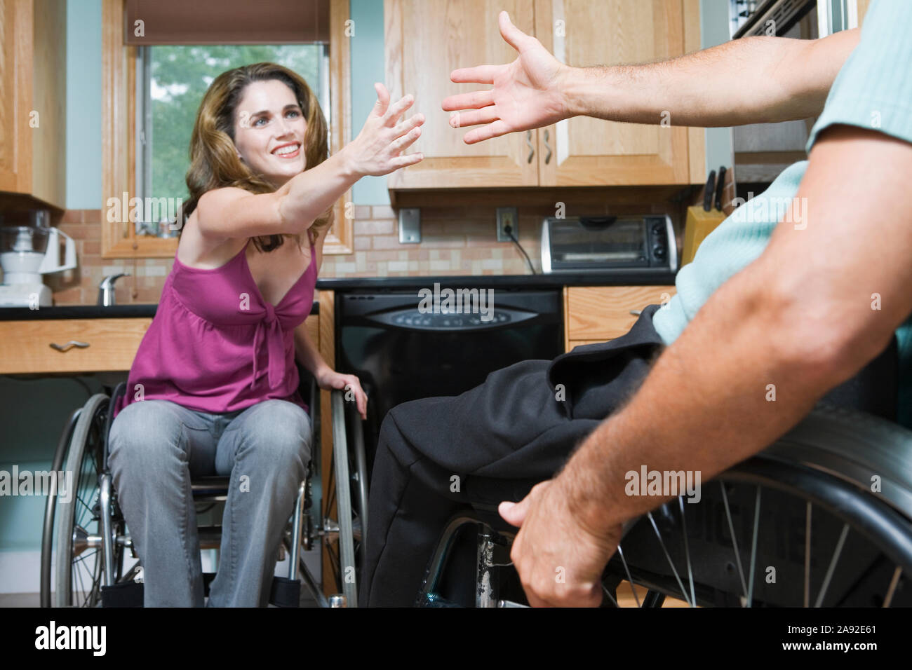 Mid adult woman sitting in a wheelchair and reaching out for another ...