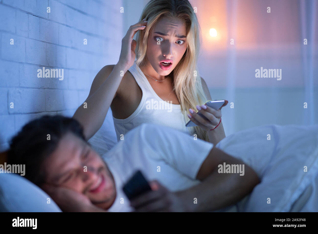 Woman Catching Boyfriend Cheater Chatting On Phone In Bed Indoor Stock ...