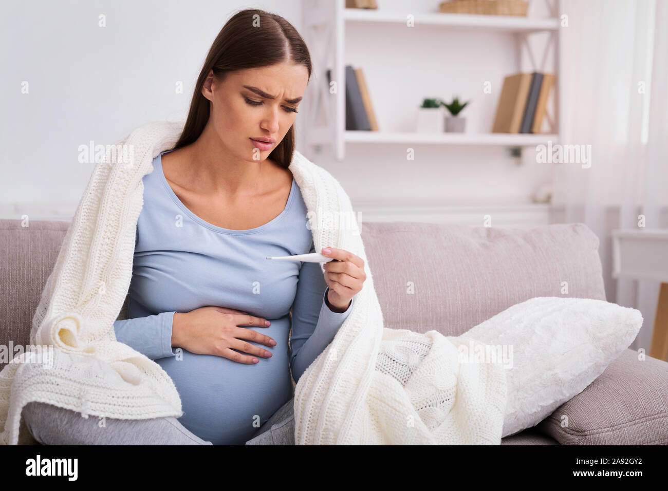Pregnant Woman Having Fever Measuring Temperature Sitting On Couch ...