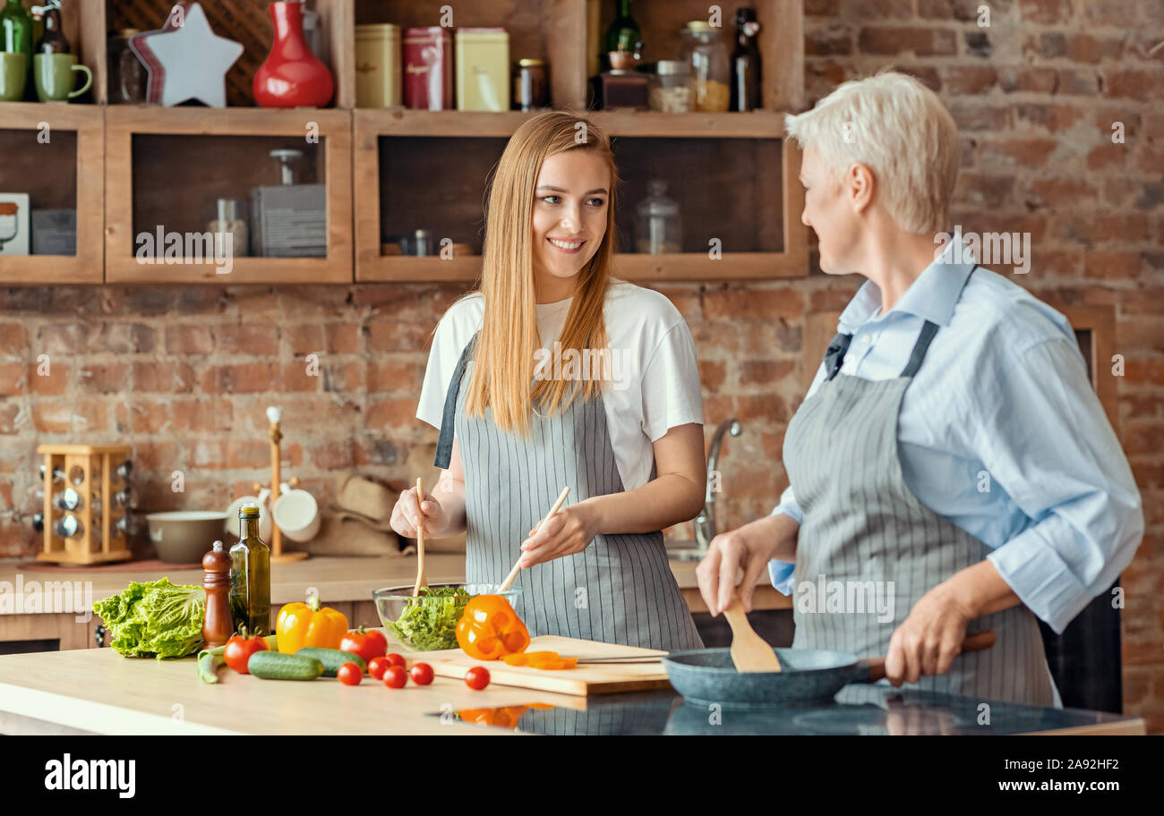Young woman talking to her mother while making dinner together Stock ...