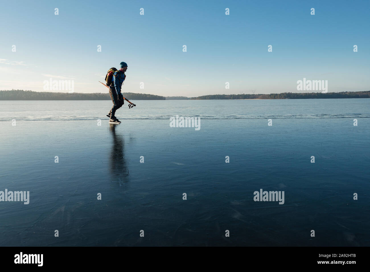 Man ice-skating on frozen lake Stock Photo - Alamy